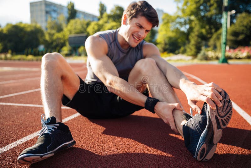 Young Male Runner Suffering from Leg Cramp on the Track Stock Photo ...