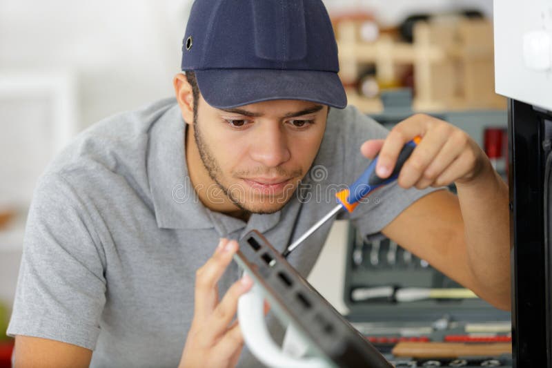 Young Male Serviceman Using Screwdriver To Assemble Oven Door Stock ...