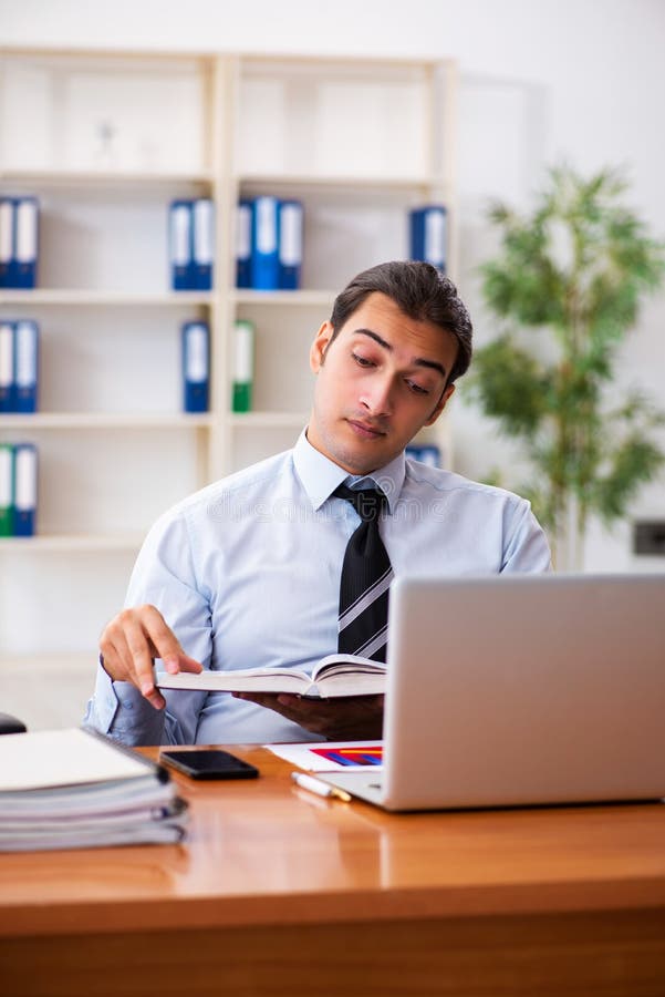 Young Male Student Employee Reading Book at Workplace Stock Image ...