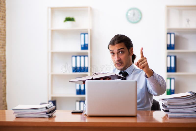 Young Male Student Employee Reading Book at Workplace Stock Photo ...