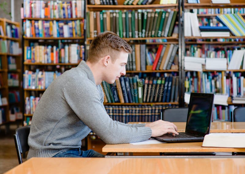 Young Male Student Typing on Laptop in the University Library Stock ...