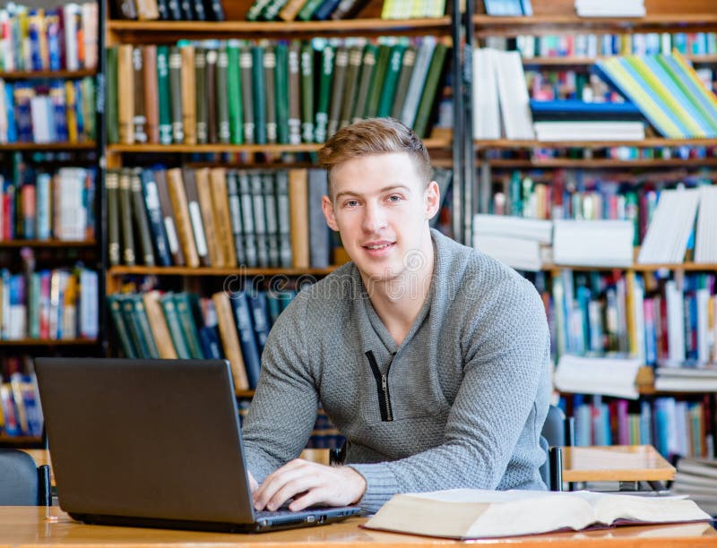 Young Male Student Typing on Laptop in the University Library Stock ...