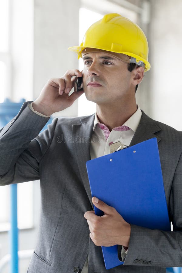 Young Male Supervisor with Clipboard Using Cell Phone in Industry Stock ...