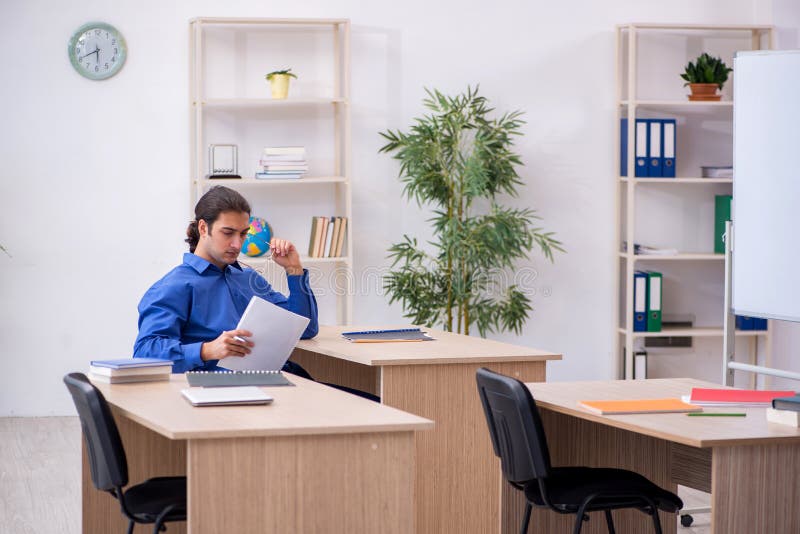 Young Male Teacher Checking Notes in the Classroom Stock Photo - Image ...