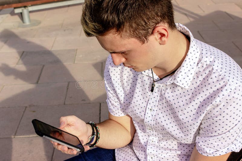 Young Male Using Mobile Phone while Sitting Outdoors Stock Photo ...