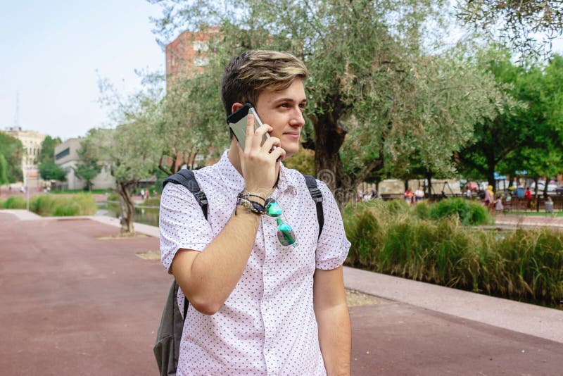 Young Man Using Mobile Phone while Walking Outdoors Stock Image - Image ...