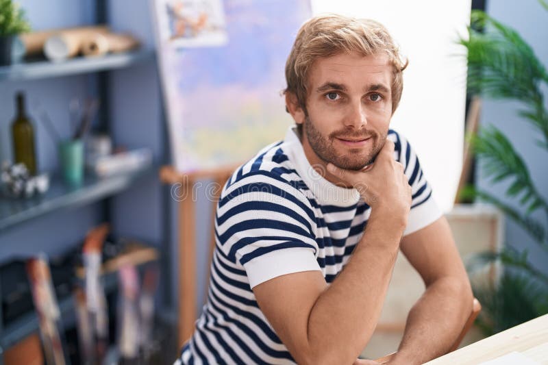 Young Man Artist Smiling Confident Sitting on Table at Art Studio Stock ...