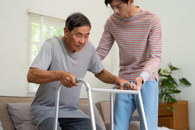 Young Man Assisting His Elderly Father with a Walker for Mobility ...