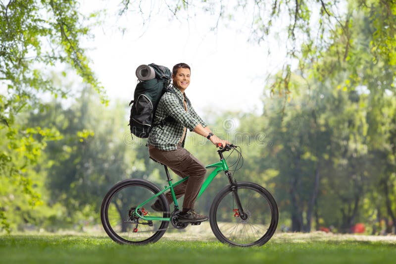 Young Man with a Backpack Riding a Bicycle in a Park Stock Photo ...