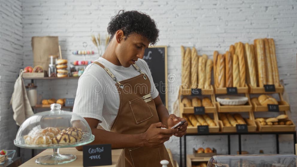 Young Man in a Bakery Looking at a Phone while Standing Next To a ...