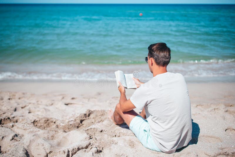 Young Man Sitting on the Beach Reading Book Stock Photo - Image of ...