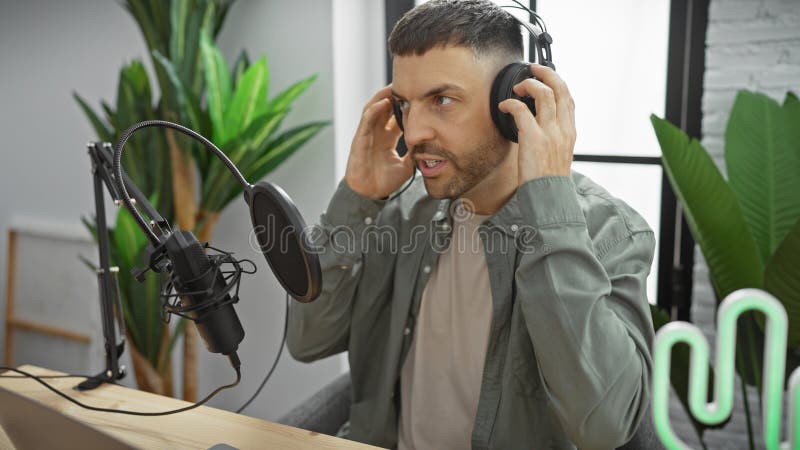 A Young Man with a Beard is Adjusting Headphones in a Modern Radio ...