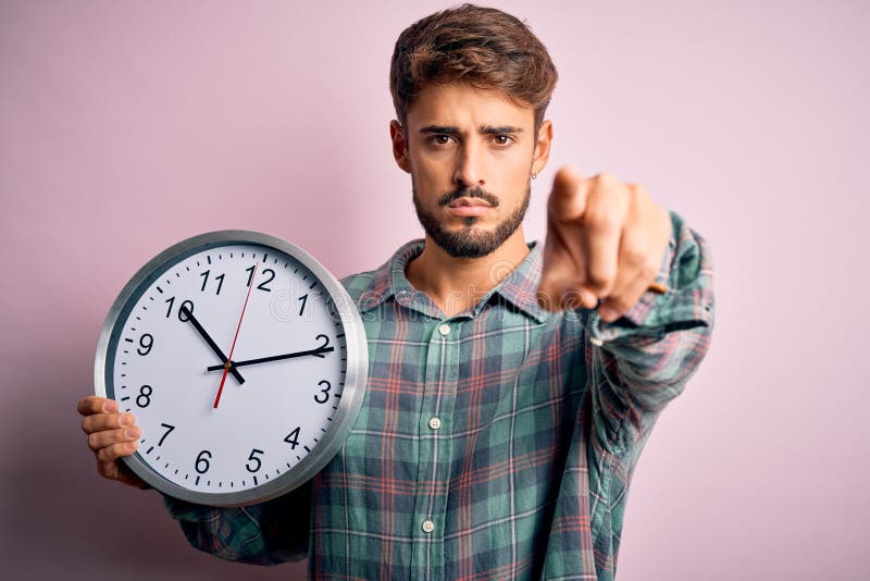 Young Man with Beard Doing Countdown Using Big Clock Over Isolated Pink ...