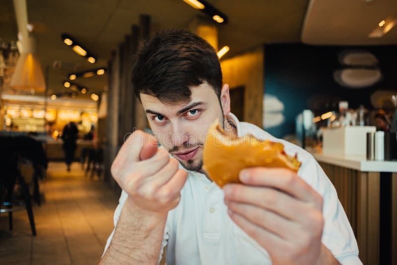 A Young Man with a Beard Eats Burger in a Nice Restaurant and Does Not ...