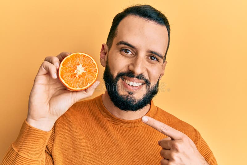 Young Man with Beard Holding Fresh Orange Smiling Happy Pointing with ...