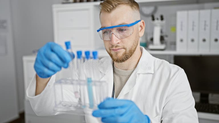 A Young Man with a Beard Performs an Experiment in a Laboratory ...