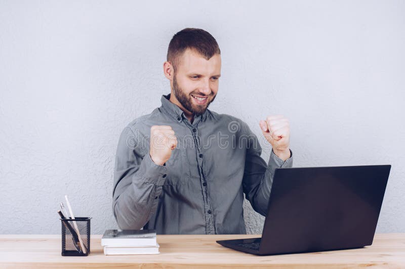 A Young Man with a Beard Sits at a Table and Works at a Computer ...