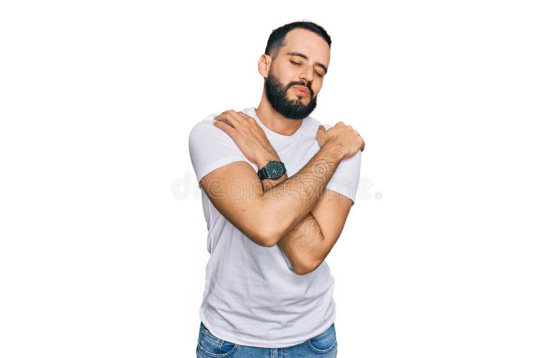 Young Man With Beard Wearing Casual White T Shirt Hugging Oneself Happy