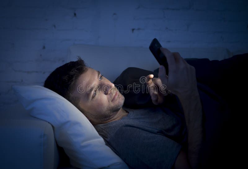 Young Man In Bed Couch At Home Late At Night Texting On Mobile Phone In ...