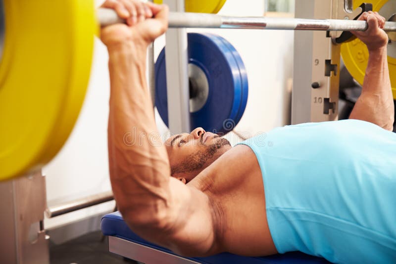 Young Man Bench Pressing Weights at a Gym, Side View Close-up Stock ...