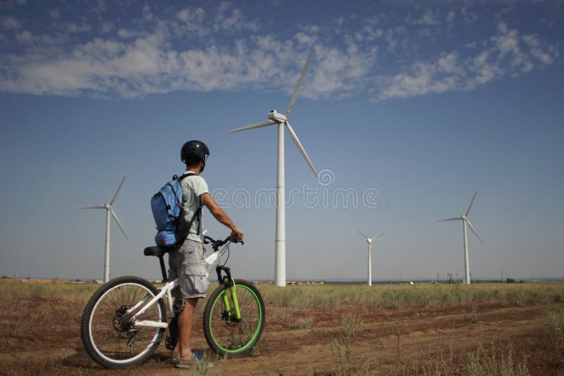A Young Man on a Bicycle Rides Past a Wind Power Plant Stock Photo ...