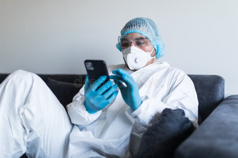 Young Man in Biohazard Clothing Using Phone and Staying at Home at Self ...