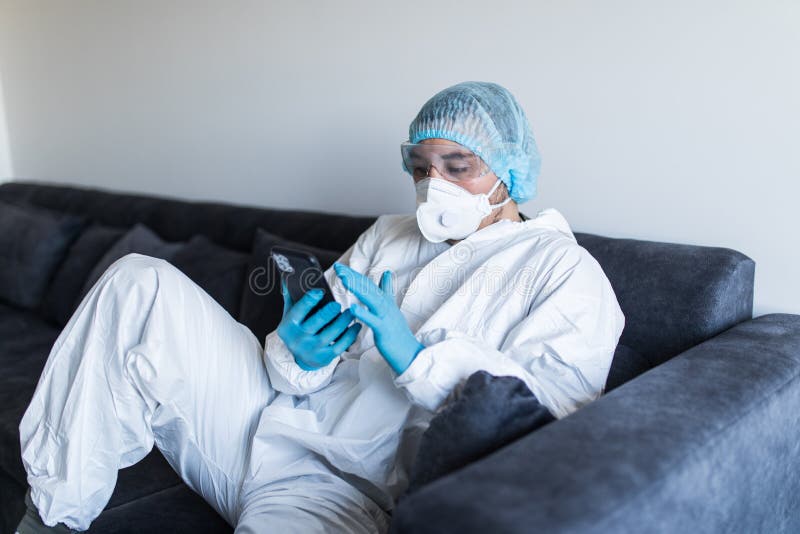 Young Man in Biohazard Clothing Using Phone and Staying at Home at Self ...