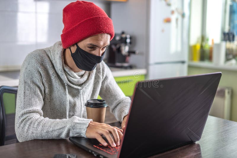 Man in a Face Mask is Using a Laptop at Home. Concept of Remote Work ...