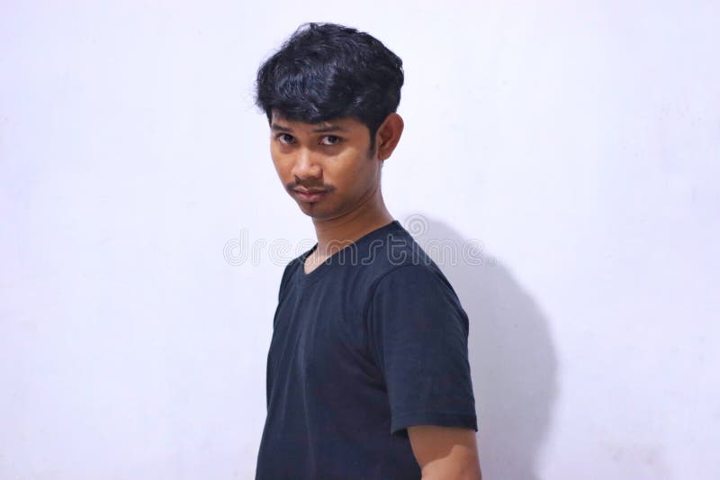 A Young Man in Black Stands in Front of a White Wall. His Serious Face ...
