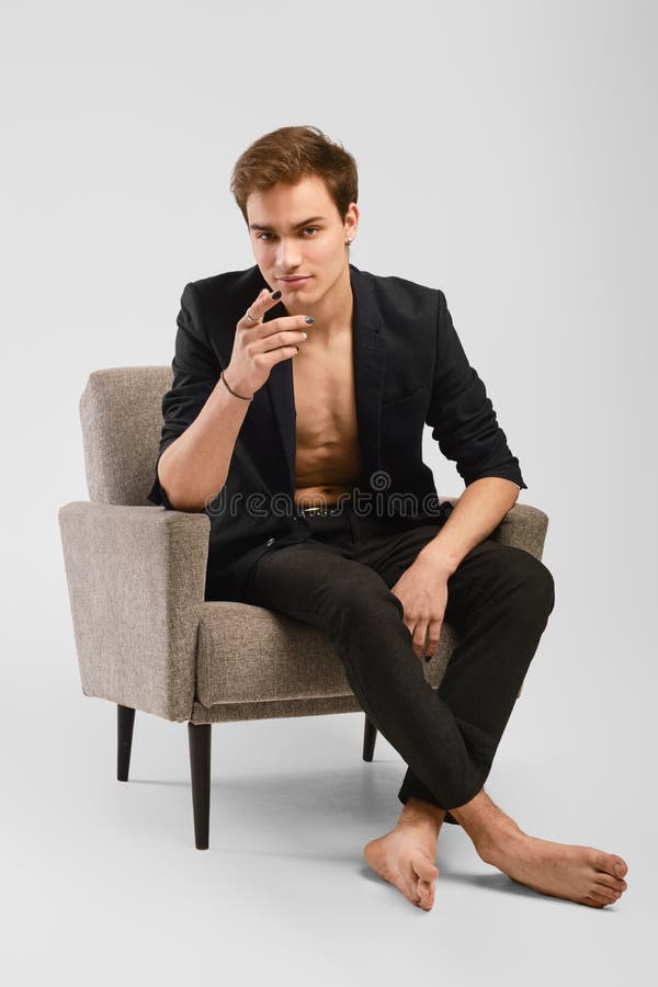 Young Man in Black Suit Siting in an Armchair and Pointing Finger ...