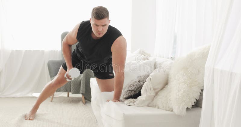 Young Man Bodybuilder is Lifting Dumbbells at Home Practicing Triceps ...