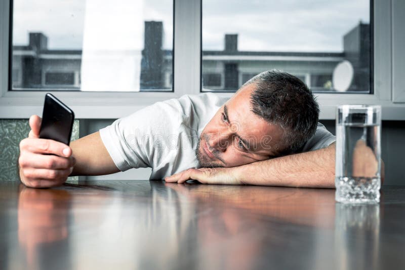 Young Man Bored Using His Smartphone. Bored Young Man Sitting in His ...