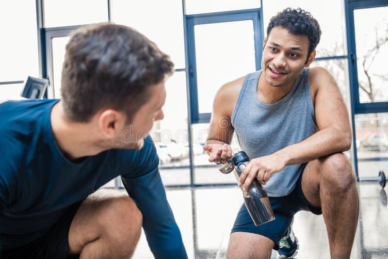 Young Man with Bottle of Water Talking To Friend Stock Photo - Image of ...