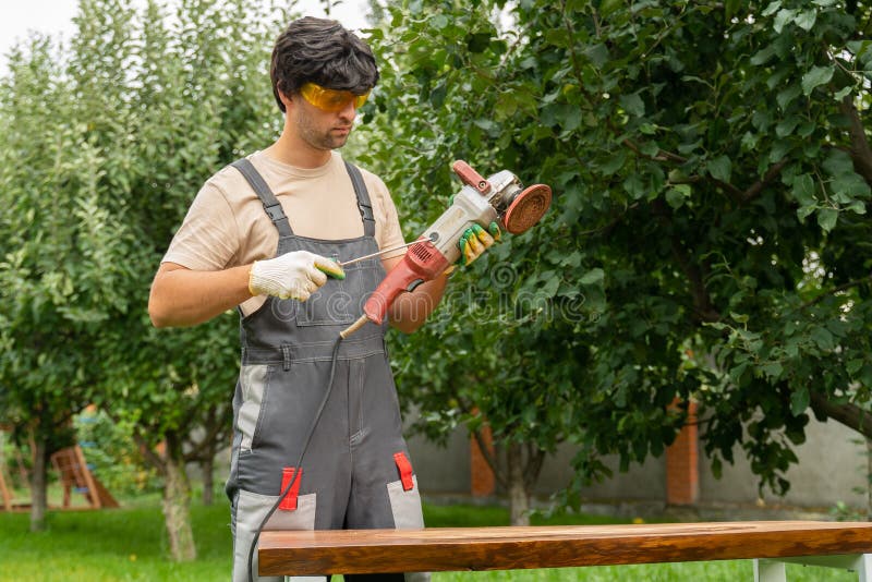 Young Man Builder Carpenter Repairs a Grinding Machine in the Backyard ...
