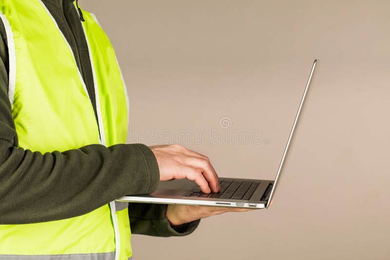 A Young Man, a Builder in the Green Safety Vest, Using a Computer, on a ...