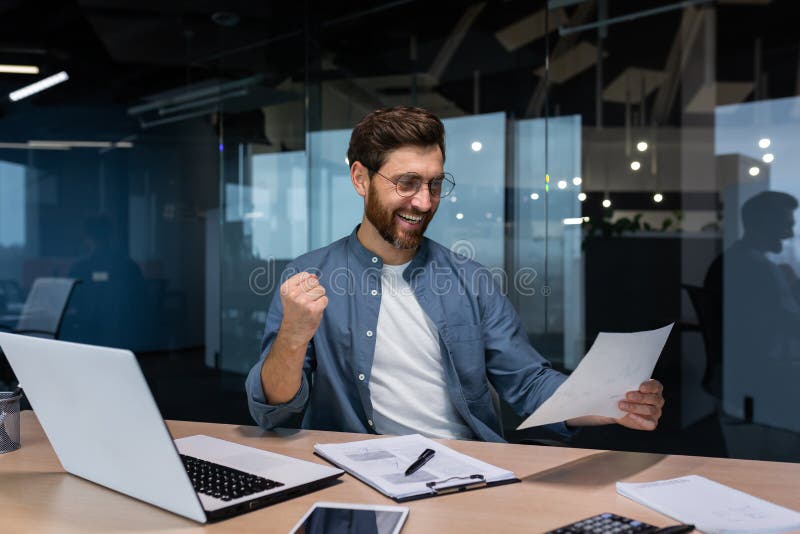 A Happy Young Man, a Businessman, a Freelancer Sits in the Office ...