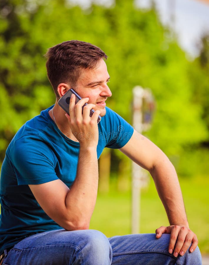 Young Man Calling Outdoors: Handsome Young Man is Sitting and Calling ...