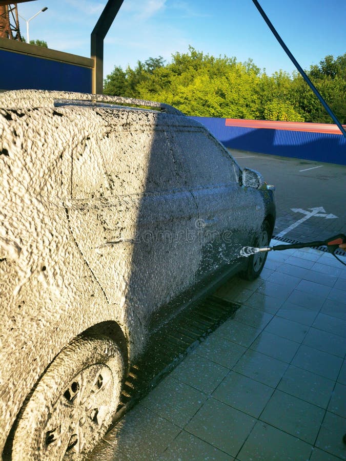 A Young Man at a Car Wash Washes the Car Under High Pressure. Selective ...