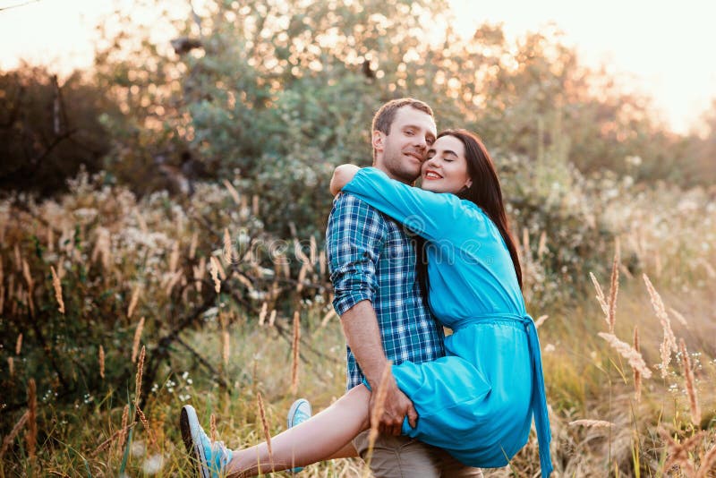 Young Man Carries In His Arms A Young Attractive Girl In A Park Stock