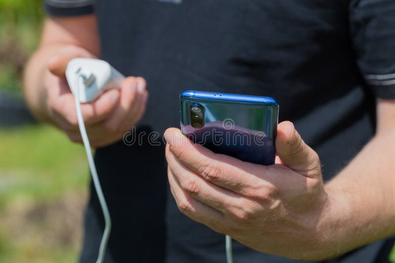 A Young Man Charges the Phone Using a Power Bank Outside Stock Photo ...
