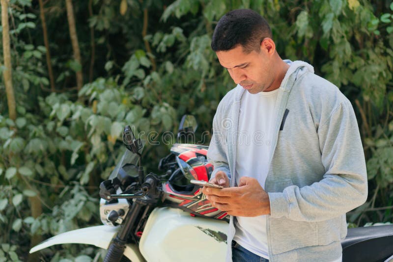 Young Man Checking His Cell Phone before Taking a Motorcycle Ride in ...