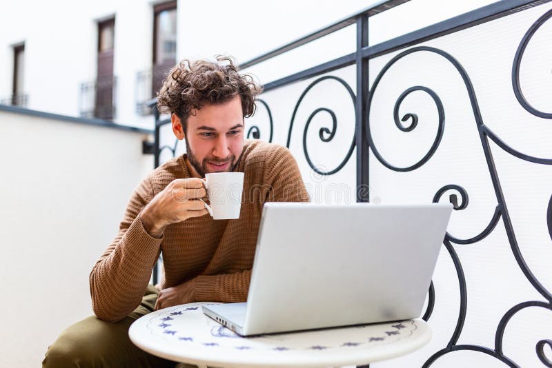 Young Man Checking His Emails on Laptop Computer and Drinking Coffee in ...