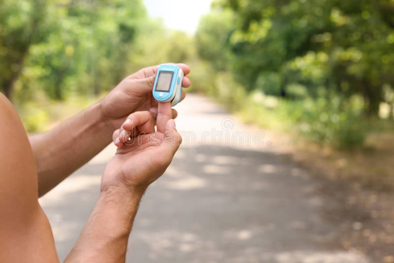 Young Man Checking Pulse with Medical Device in Park, Closeup Stock ...