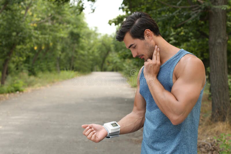 Young Man Checking Pulse with Medical Device after Training in Park ...
