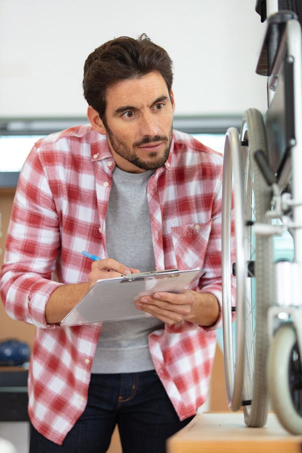 Young Man Checking Wheelchair at Workplace Stock Photo - Image of ...
