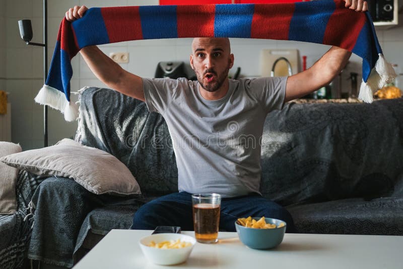 Young Man Cheering on His Team in the Sofa with a Scarf Stock Photo ...