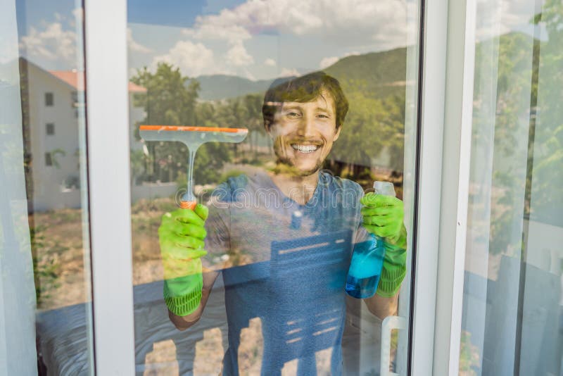 A Young Man Cleaning the Window with a Window Cleaner Stock Photo ...