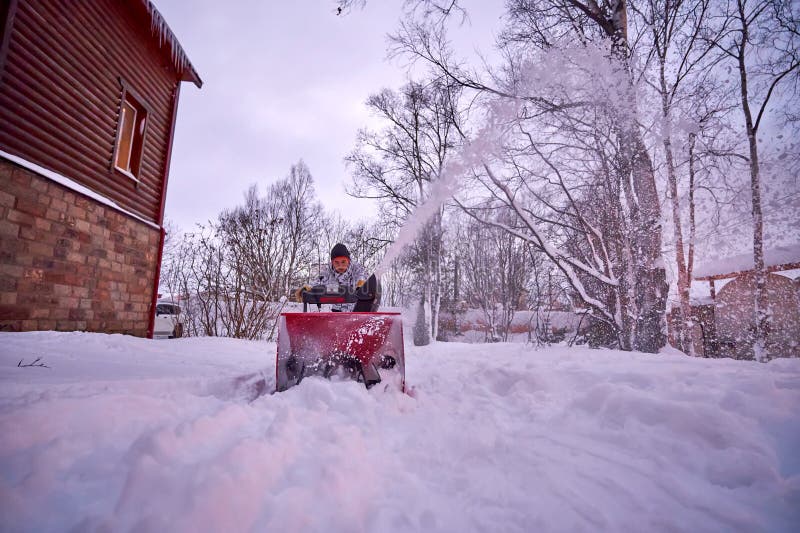 A Young Man Clears Snow with a Snow Blower in His Yard. Stock Image ...