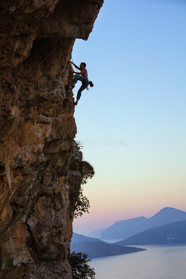 Young Man Climbing Vertical Cliff at Sunset Stock Photo - Image of ...