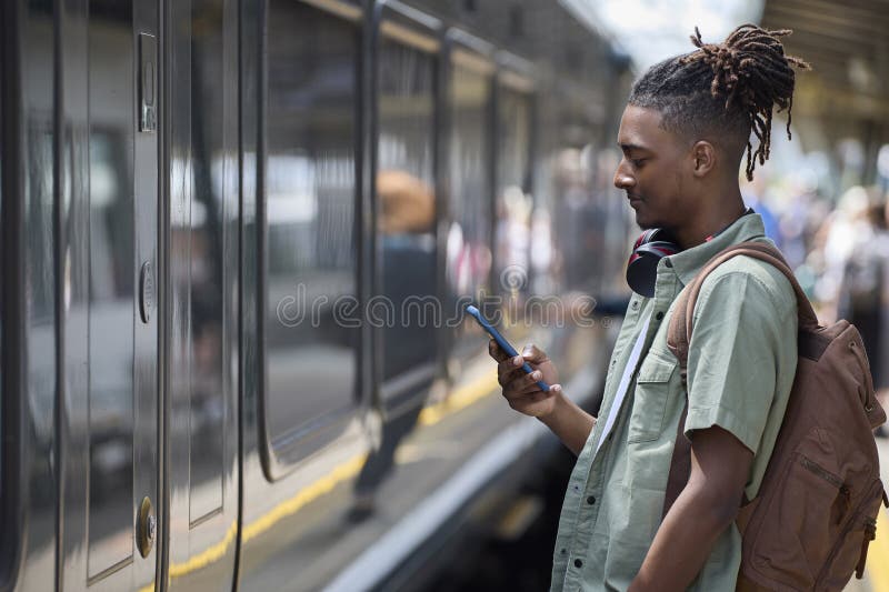 Young Man Commuting To Work on Train Standing on Platform Looking at ...